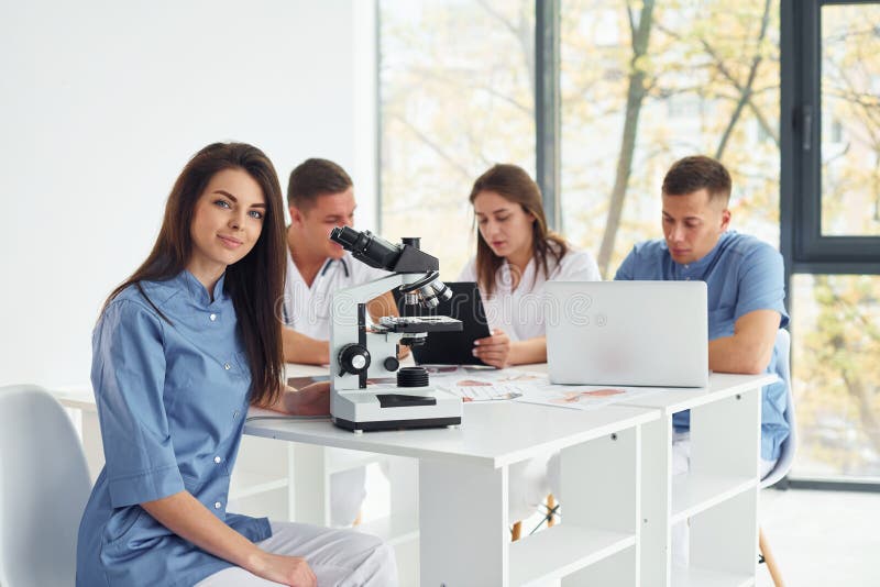 Using Microscope. Group of Young Doctors is Working Together in the ...