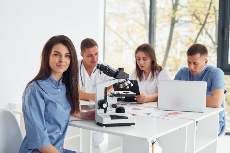 Using Microscope. Group of Young Doctors is Working Together in the ...