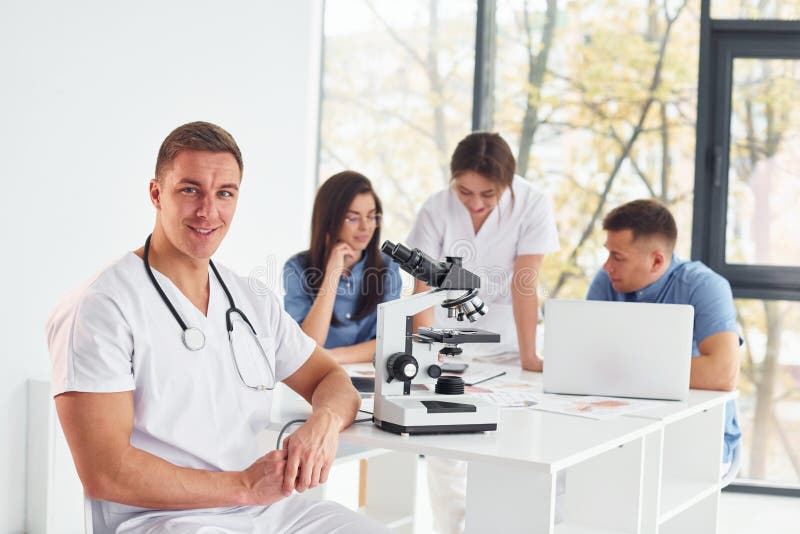 Using Microscope. Group of Young Doctors is Working Together in the ...
