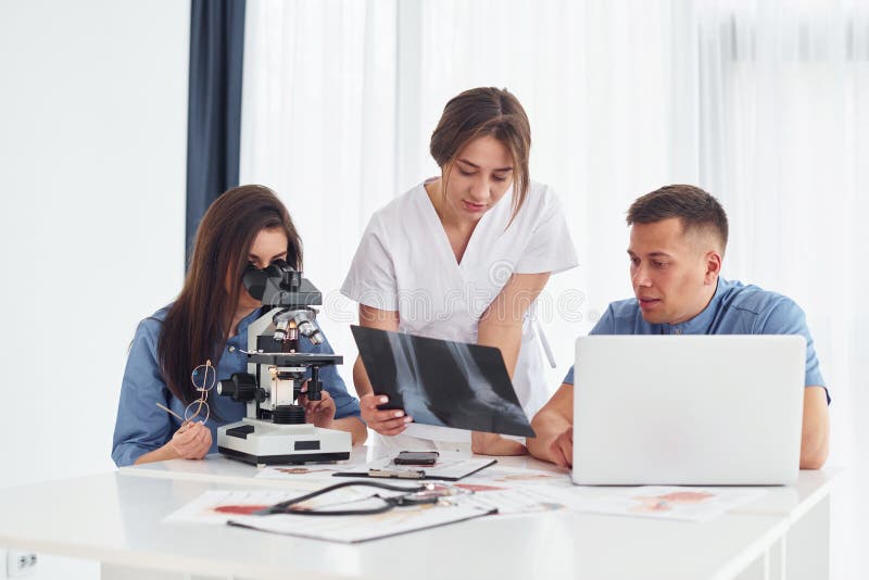 Using Microscope. Group of Young Doctors is Working Together in the ...