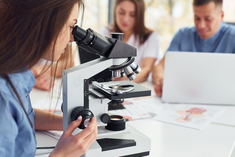 Using Microscope. Group of Young Doctors is Working Together in the ...