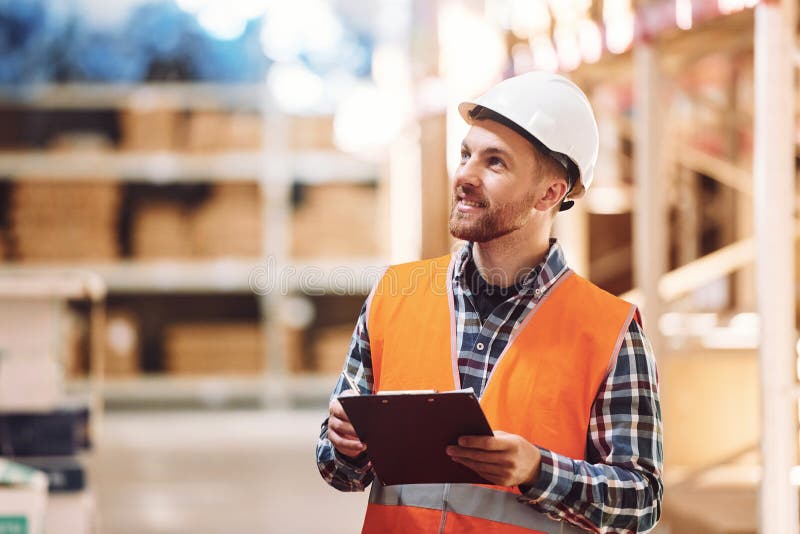 Using Notepad. Employee in Uniform is Working in the Storage at Daytime ...