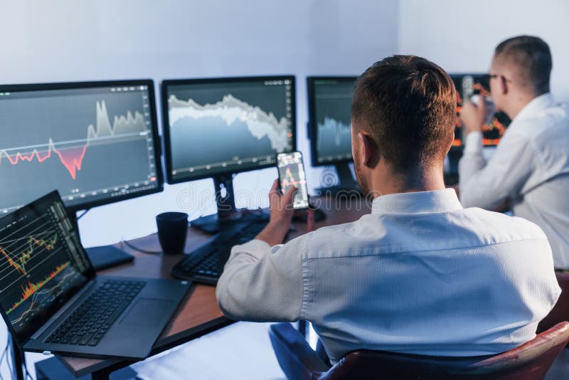 Using the Phone. Two Stock Traders Working in the Office with Exchange ...