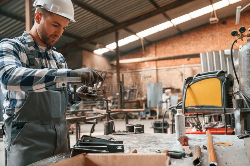 Using Professional Tools. Factory Male Worker in Uniform is Indoors ...
