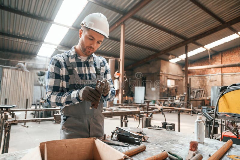 Using Professional Tools. Factory Male Worker in Uniform is Indoors ...