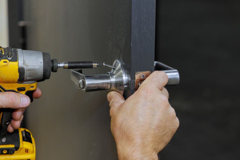 Using a Screwdriver, Carpenter Installs Lock Handles on Room Door Stock ...