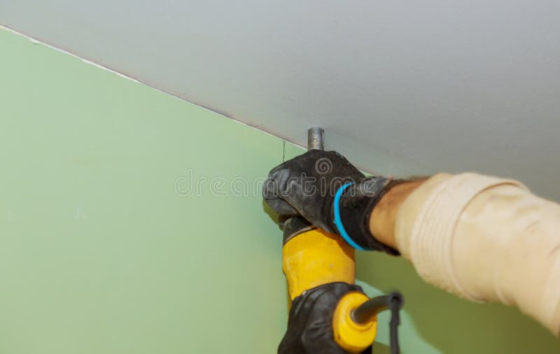 Using a Screwdriver and Drywall Screws, a Worker Screws the Drywall ...