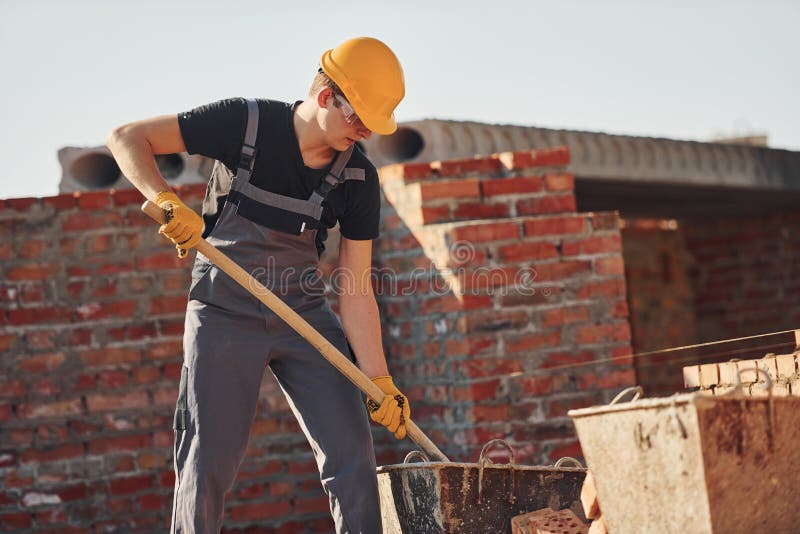 Using Showel. Construction Worker in Uniform and Safety Equipment Have ...