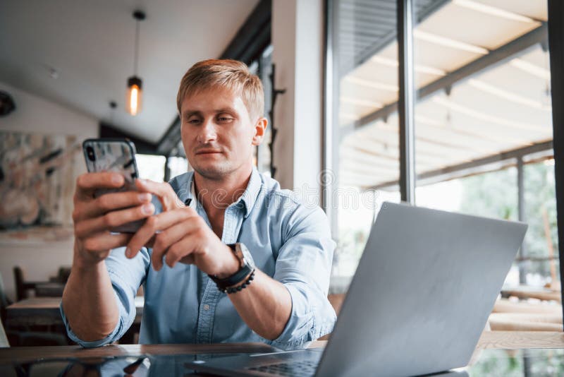 Using Smartphone. Front View of Guy that is in Modern Cafe with His ...