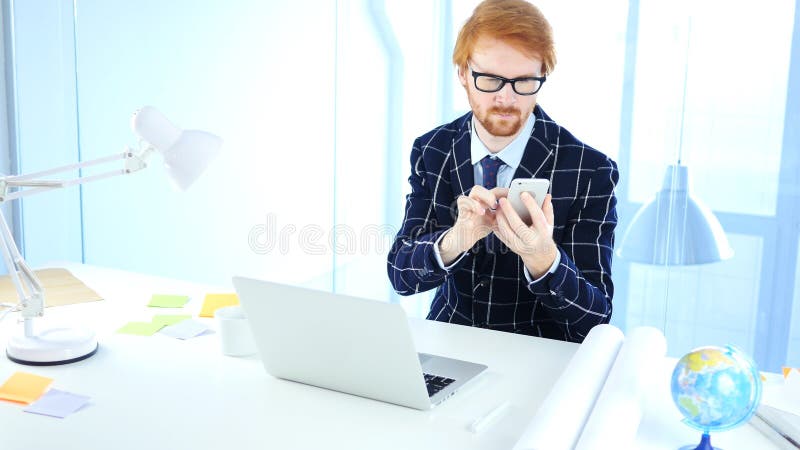 Using Smartphone at Work, Man with Red Hairs Sitting in Office Stock ...