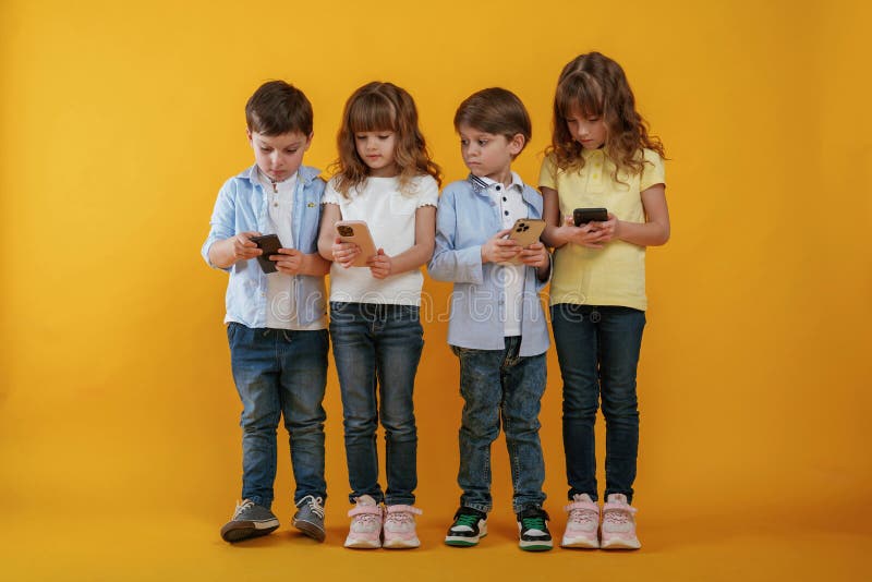 Using Smartphones. Kids are Together Against Yellow Background Stock ...