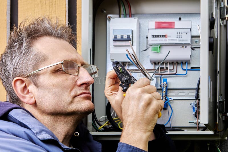An Electrician Strips Insulation from Wire of Three-phase Power Cable ...