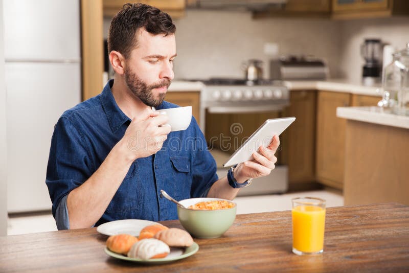 Using a Tablet and Eating Breakfast Stock Photo - Image of denim, adult ...