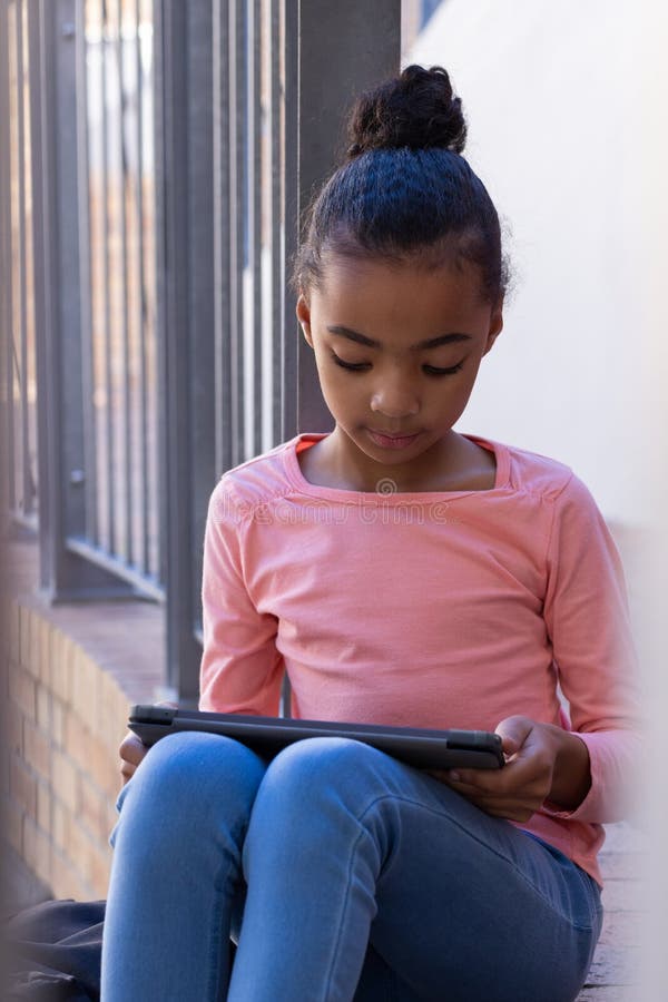 Using Tablet, Girl Sitting and Studying in School Hallway, Focused on ...