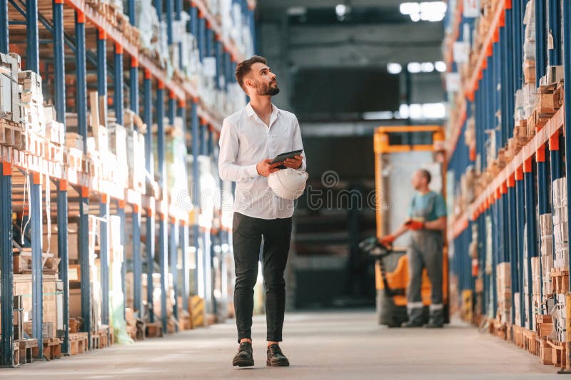 Using Tablet To Check the Products. Storage Worker is in the Warehouse ...