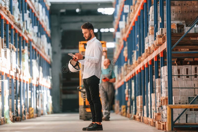 Using Tablet To Check the Products. Storage Worker is in the Warehouse ...