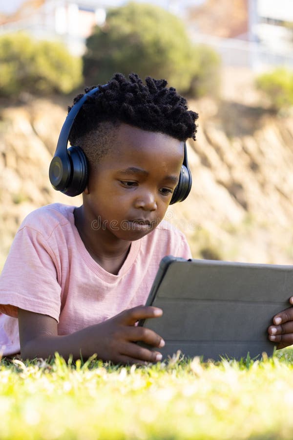 Using Tablet and Wearing Headphones, African American Boy Studying ...