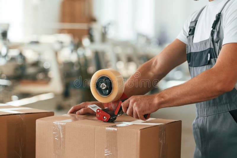 Using Tape, Packing the Product. Handsome Man is Working at the Factory ...