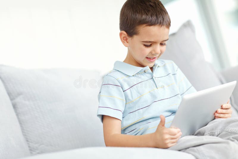 Using Technology at a Young Age. a Little Boy Sitting on a Sofa and ...