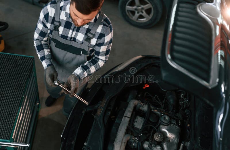 Using the Tool and Fixing the Car. Man in Uniform is Working in the ...