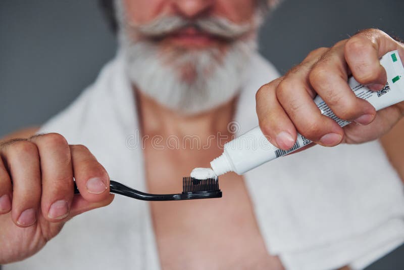 Using Toothpaste. Stylish Modern Senior Man with Gray Hair and Beard is ...