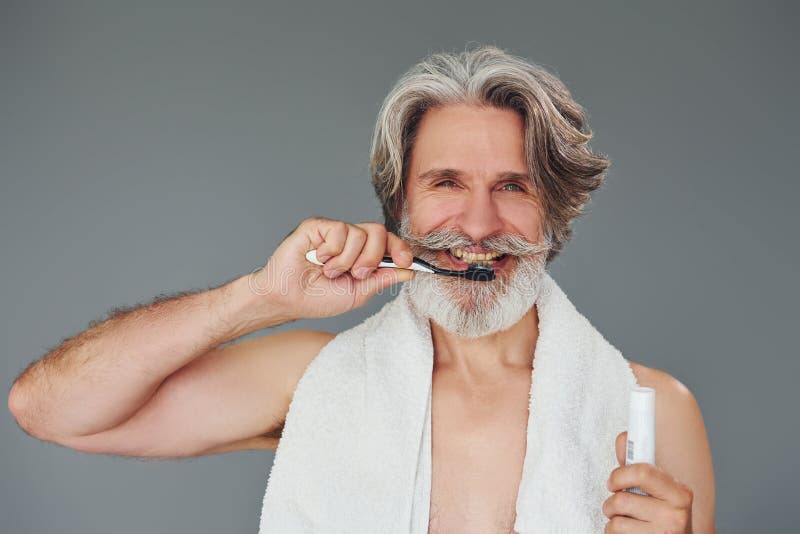 Using Toothpaste. Stylish Modern Senior Man with Gray Hair and Beard is ...