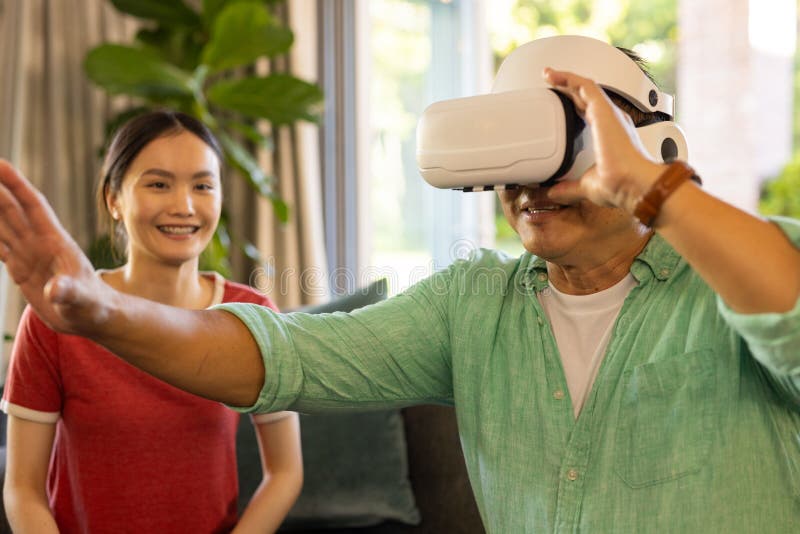 Using VR Headset, Father Interacting with Virtual Environment while Daughter Watching Stock ...