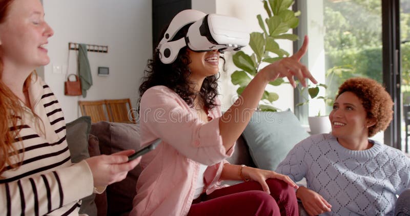 Using VR Headset, Woman Interacting with Virtual Environment while Female Friends Watch Stock ...