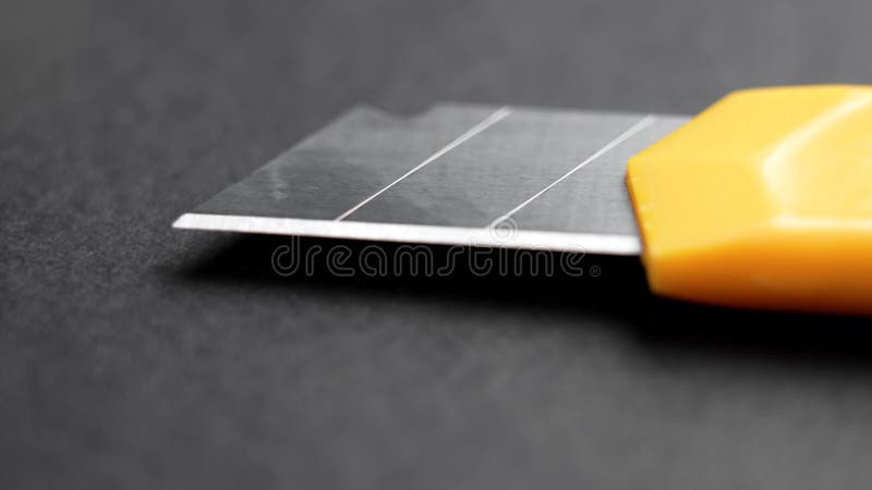 A Utility Knife with a Retractable Segmented Blade on a Black Paper ...