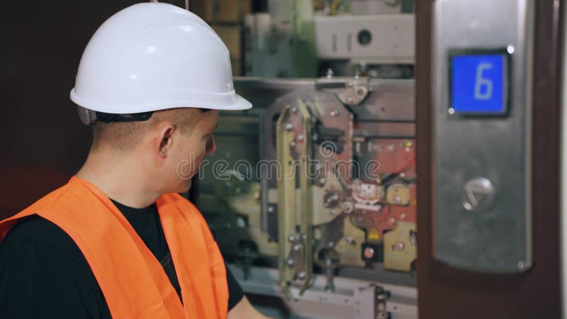 A Utility Worker Repairs an Elevator in a Residential Complex. a Repairman in Uniform is ...