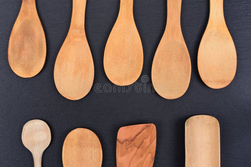 Various Empty Wooden Spoons Face Each Other on a Dark Plate Stock Photo ...