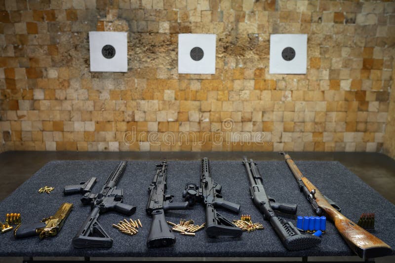 Various Firearms on a Table in a Shooting Range, Paper Targets Hang on ...