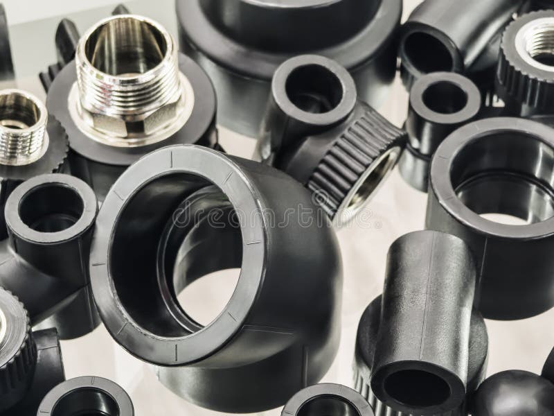 Assorted Plastic Plumbing Fittings Arranged on a Reflective Surface in ...