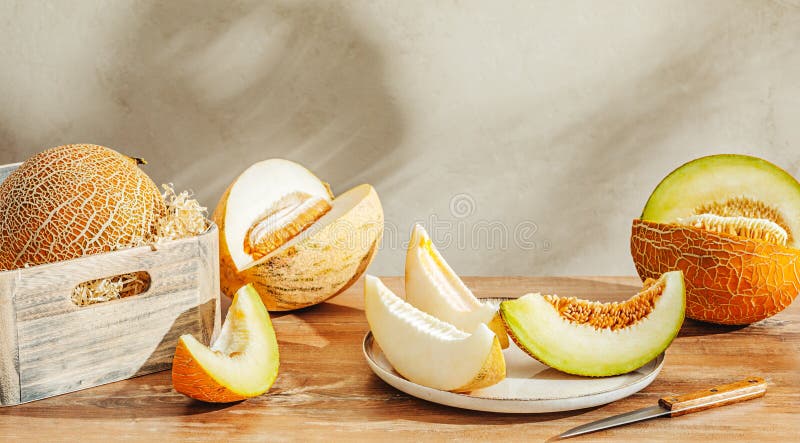 Various Sliced Melons on Wooden Table by Stone Wall Stock Photo - Image ...
