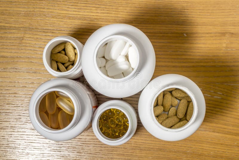 Various Tablets and Capsules in Jars Lie on a Wooden Surface Stock ...