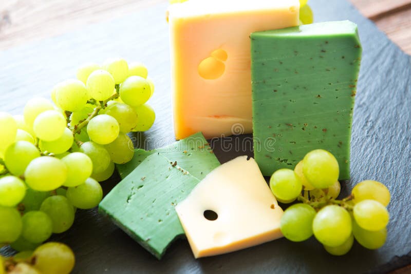 Various Types of Cheese with Green Grapes on Black Slate Cheeseboard on ...