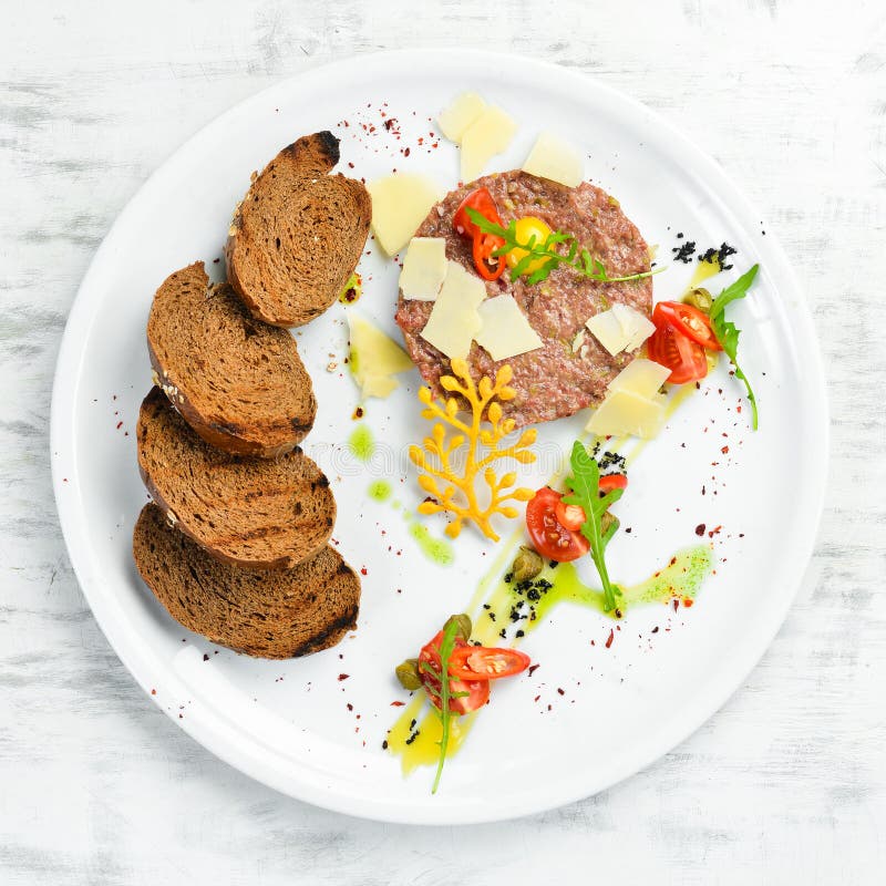 Veal Tar-tar, with Toast Bread and Vegetables on a White Plate. Stock ...