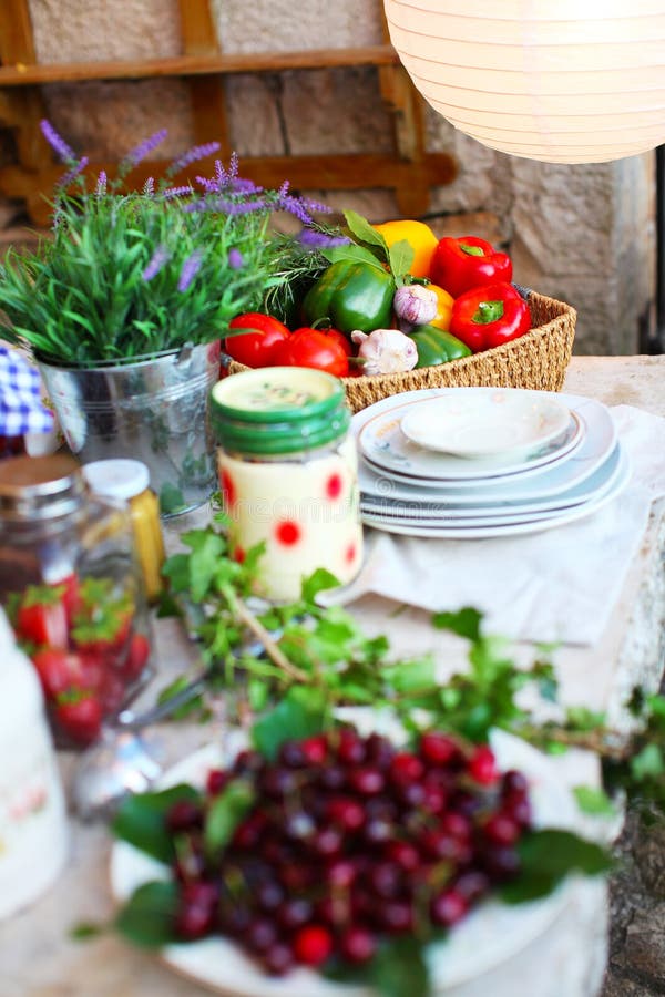 Vegetables and Cherries on a Picnic Table with Plates and Flowers Stock ...
