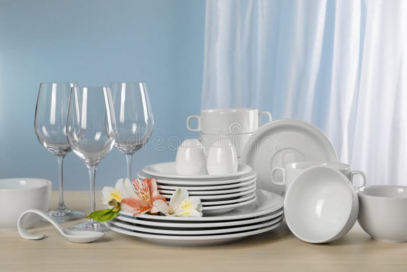 Verres Et Vaisselle Propre Avec Fleurs Sur Table Gris Clair Photo stock ...