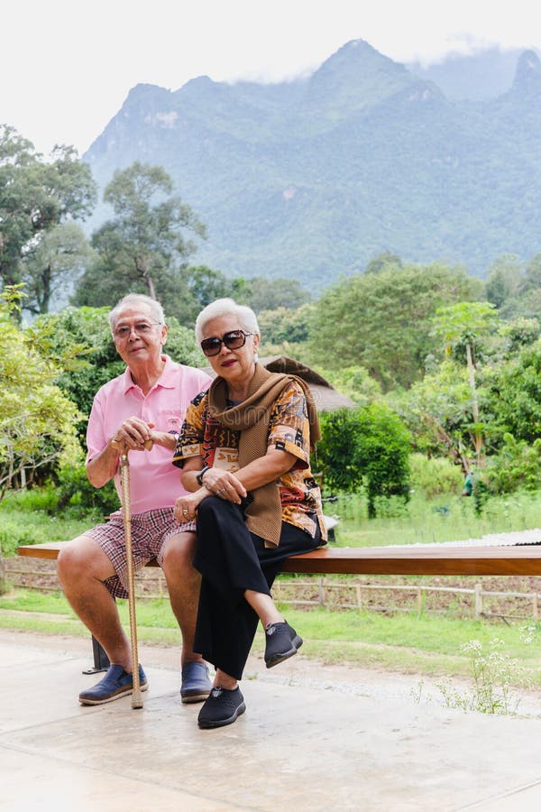 Vertical of Asian Senior Couple Sit on a Bench on Vacation Outdoors ...