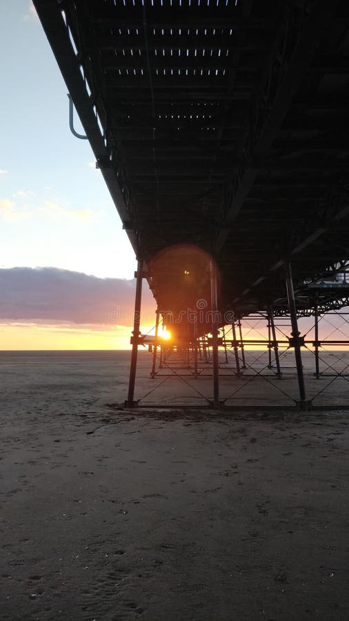 Vertical of a Beautiful Sunset at a Sandy Beach with a Pier Stock Image ...