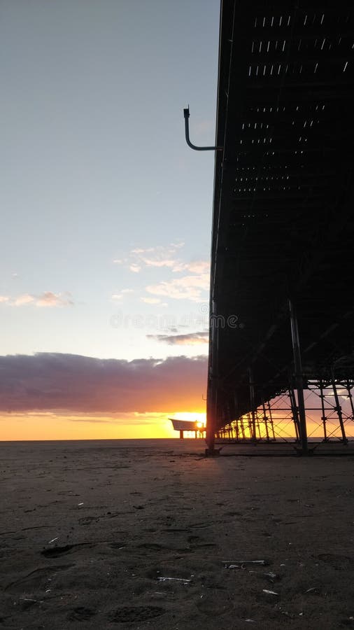 Vertical of a Beautiful Sunset at a Sandy Beach with a Pier Stock Image ...