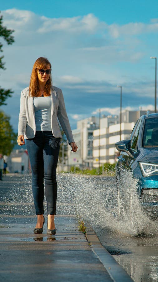 VERTICAL: Businesswoman Walking Along Sidewalk Gets Splashed by ...