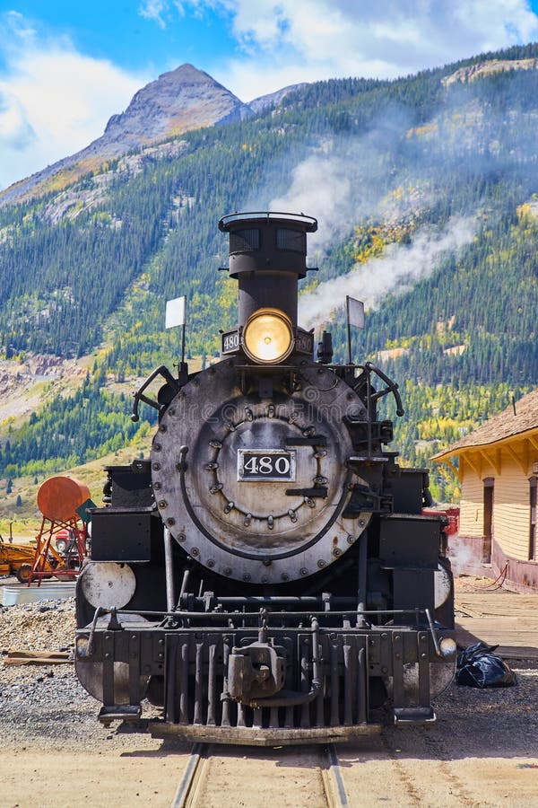 Vertical Close-up Front of Locomotive Train with Wall of Mountains in ...