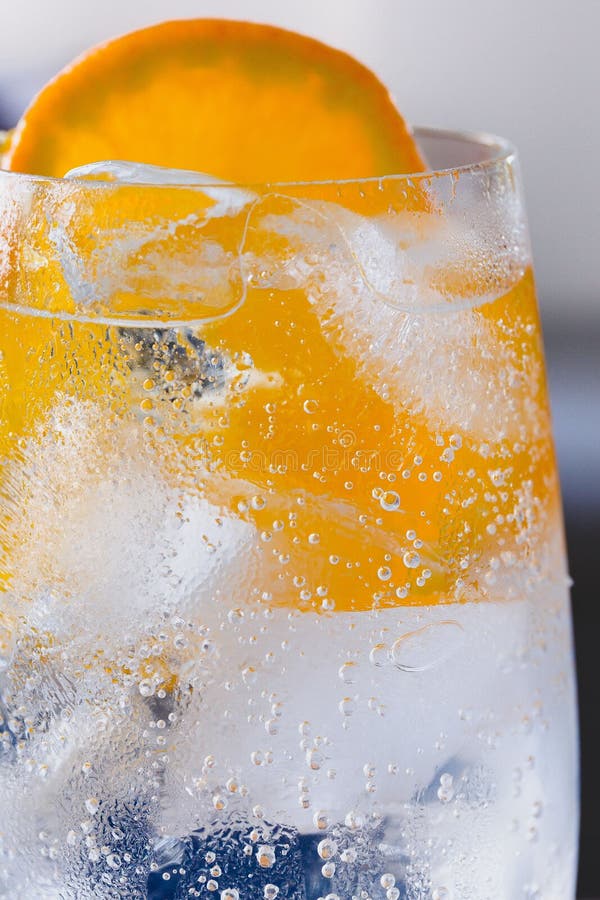 Vertical Close-up View of an Orange Slice in a Class with Bubbly Cold ...