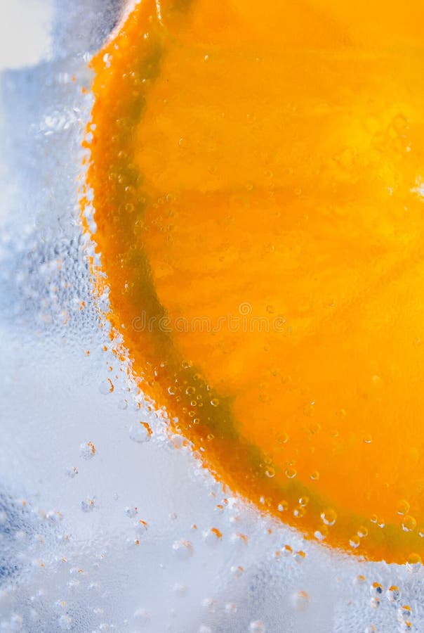 Vertical Close-up View of an Orange Slice in a Class with Bubbly Cold ...
