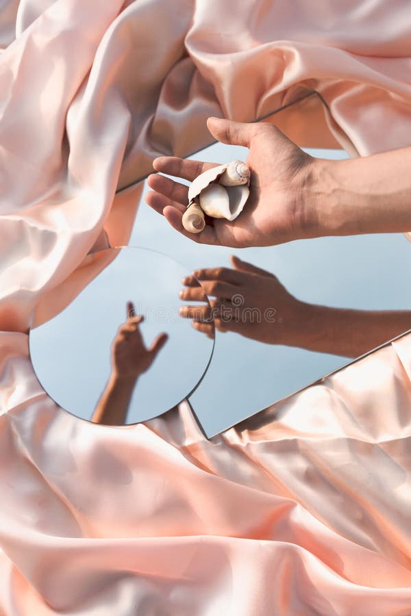Vertical Closeup of a Hand Holding Shells and Reflecting in the Mirror ...