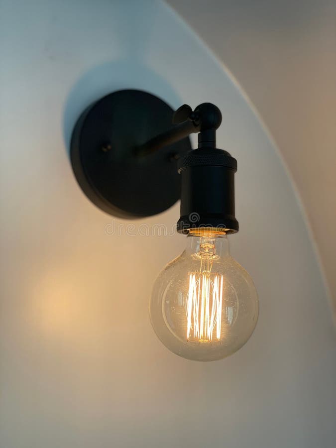 Vertical Closeup of a Light Bulb Hanging on a White Wall Stock Image ...