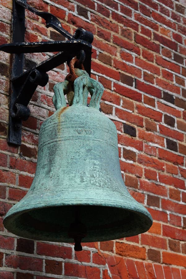 Vertical Closeup of an Old Rusty Bell Hanging on a Brick Wall of a ...