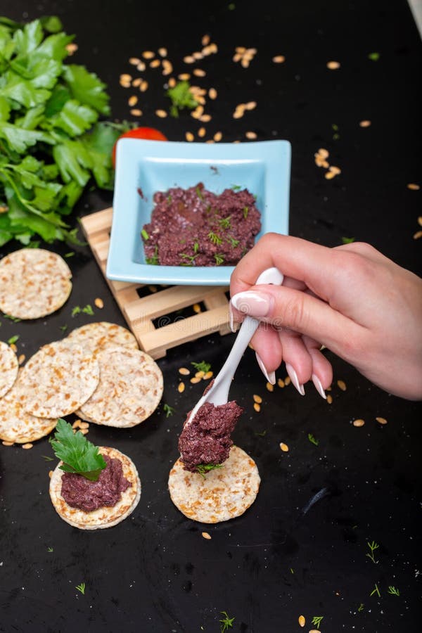 Vertical Closeup of a Person Putting Olive Paste on a Cracker Under the ...